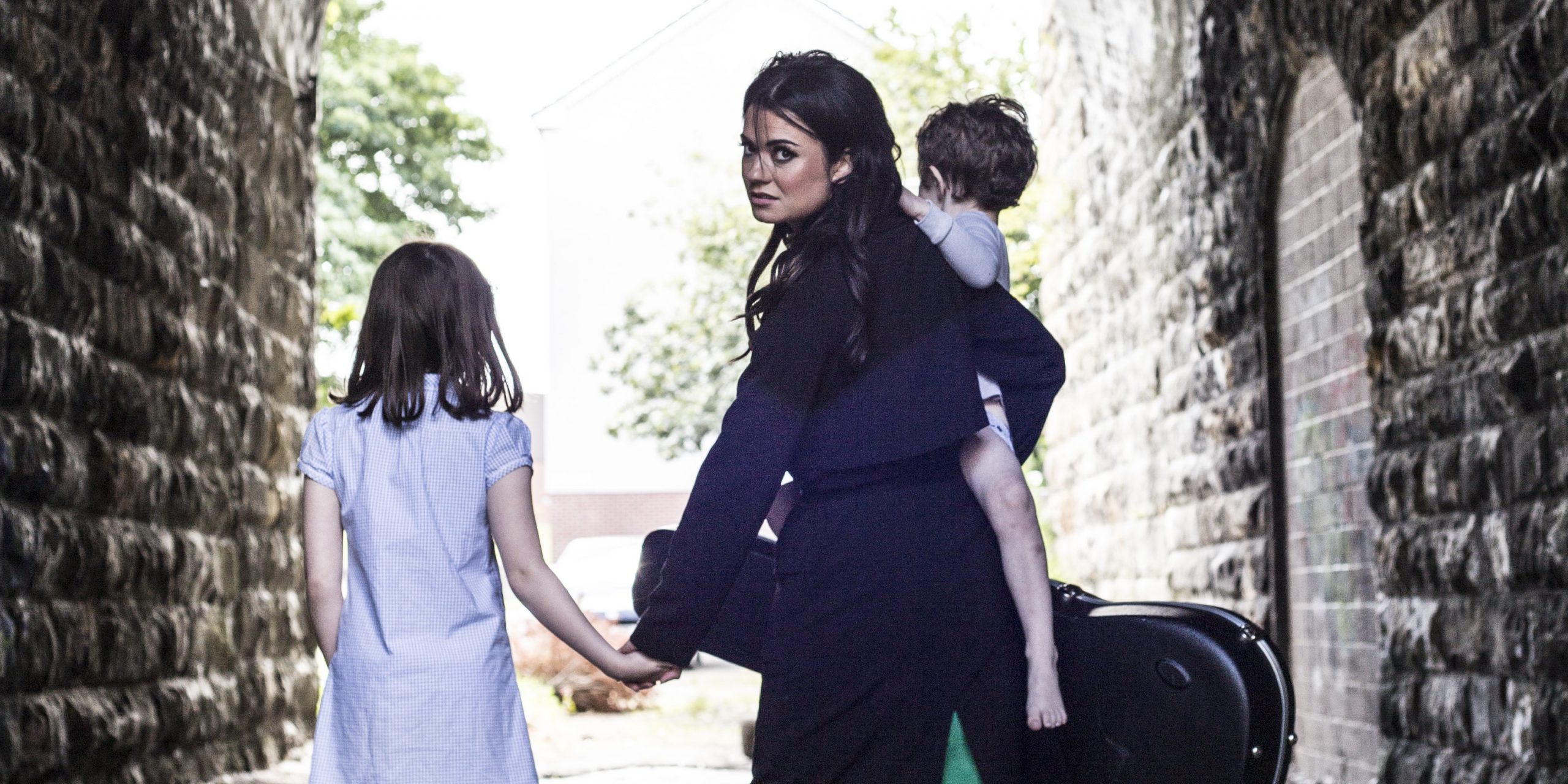 A woman with children and a guitar in a short tunnel.